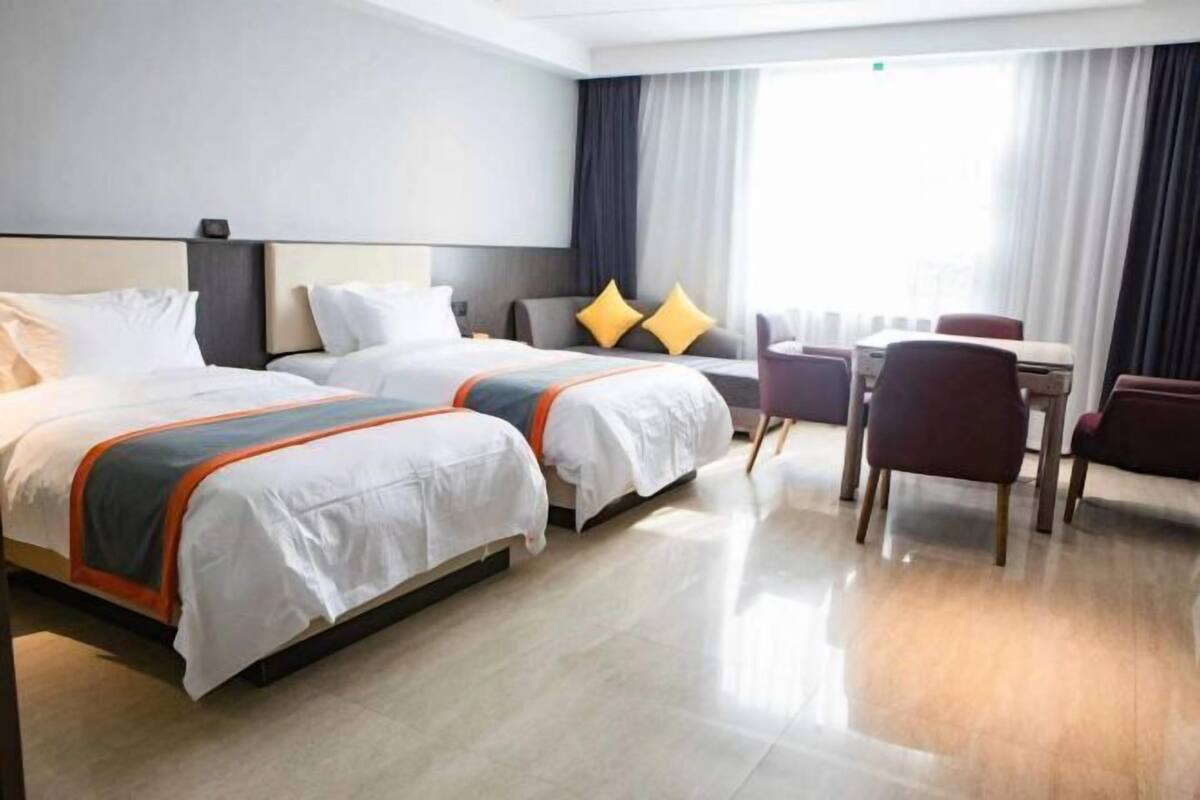 Quarto de hotel com duas camas, uma escrivaninha e uma cadeira.