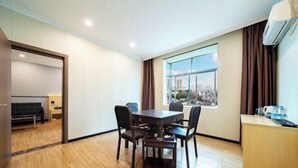 Quarto de hotel moderno com área de refeições, uma janela grande com vista para a cidade e uma cozinha compacta.