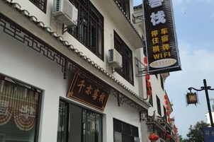 Um edifício com elementos arquitetônicos tradicionais chineses, incluindo molduras de janelas ornamentadas e uma placa com caracteres chineses.