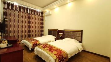 Quarto de hotel com duas camas, uma escrivaninha e cortina estampada.