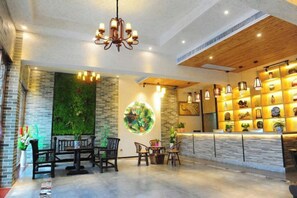 Interior moderno com área de refeições, balcão de recepção e parede decorada.