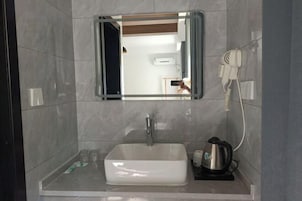 Casa de banho com uma pia retangular, espelho, secador de cabelo e telefone.