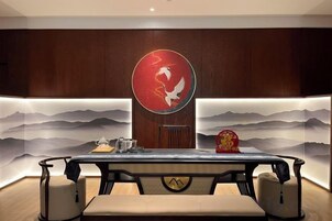 Um quarto com uma mesa de jantar, cadeiras, um banco, uma parede com uma obra de arte circular e um mural com paisagem montanhosa.