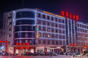 Um hotel de vários andares com fachada curva, letreiros iluminados e entrada imponente.