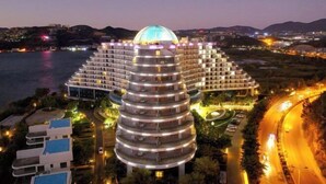 Um hotel moderno com várias estruturas circulares, uma grande cúpula central e localização à beira-mar.