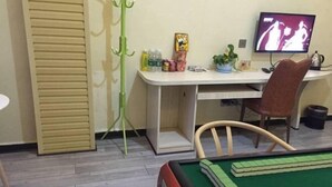 Um quarto com mesa de bilhar, escrivaninha com monitor de computador e uma cadeira.