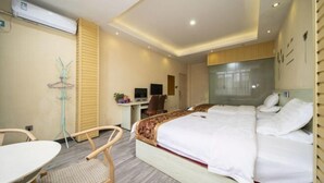 Quarto de hotel com cama, escrivaninha, cadeira e uma pequena mesa.