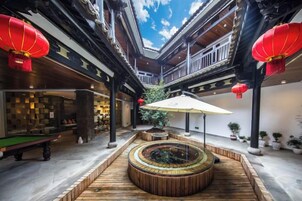 Pátio interno com banco de madeira, plantas em vasos e lanternas vermelhas.