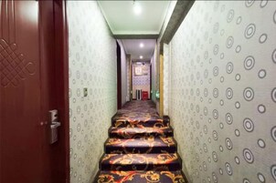Corredor com paredes estampadas e escadas com carpete que levam a um quarto.