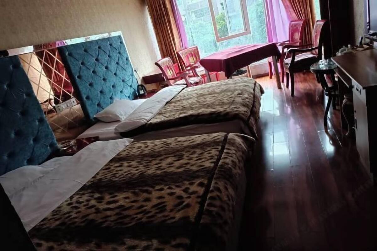 Quarto com duas camas, uma mesa, cadeiras e uma escrivaninha.
