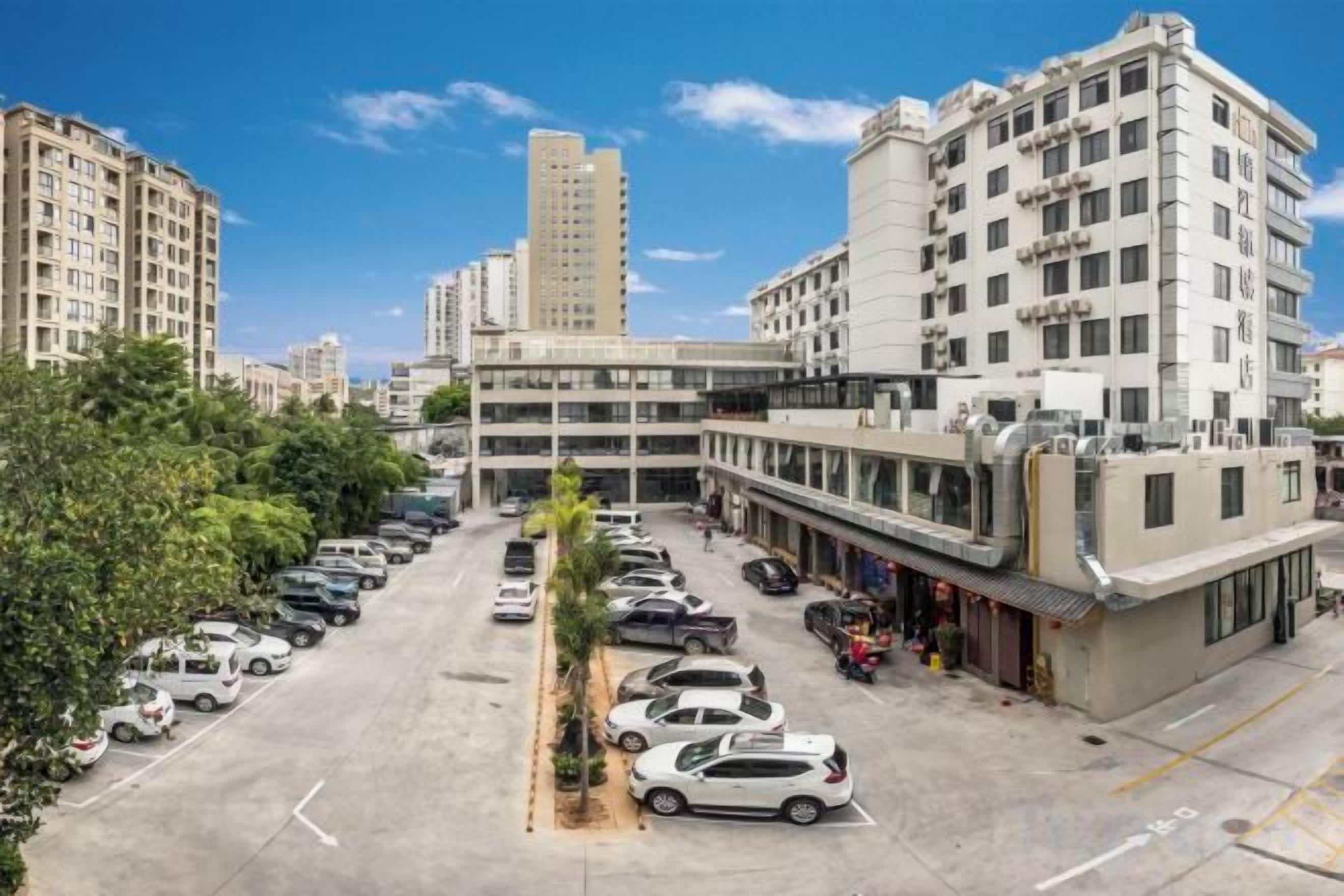 Um parque de estacionamento com vários andares, com uma fileira de carros estacionados, rodeado por edifícios com estabelecimentos comerciais no rés-do-chão.