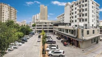Um parque de estacionamento com vários andares, com uma fileira de carros estacionados, rodeado por edifícios com estabelecimentos comerciais no rés-do-chão.