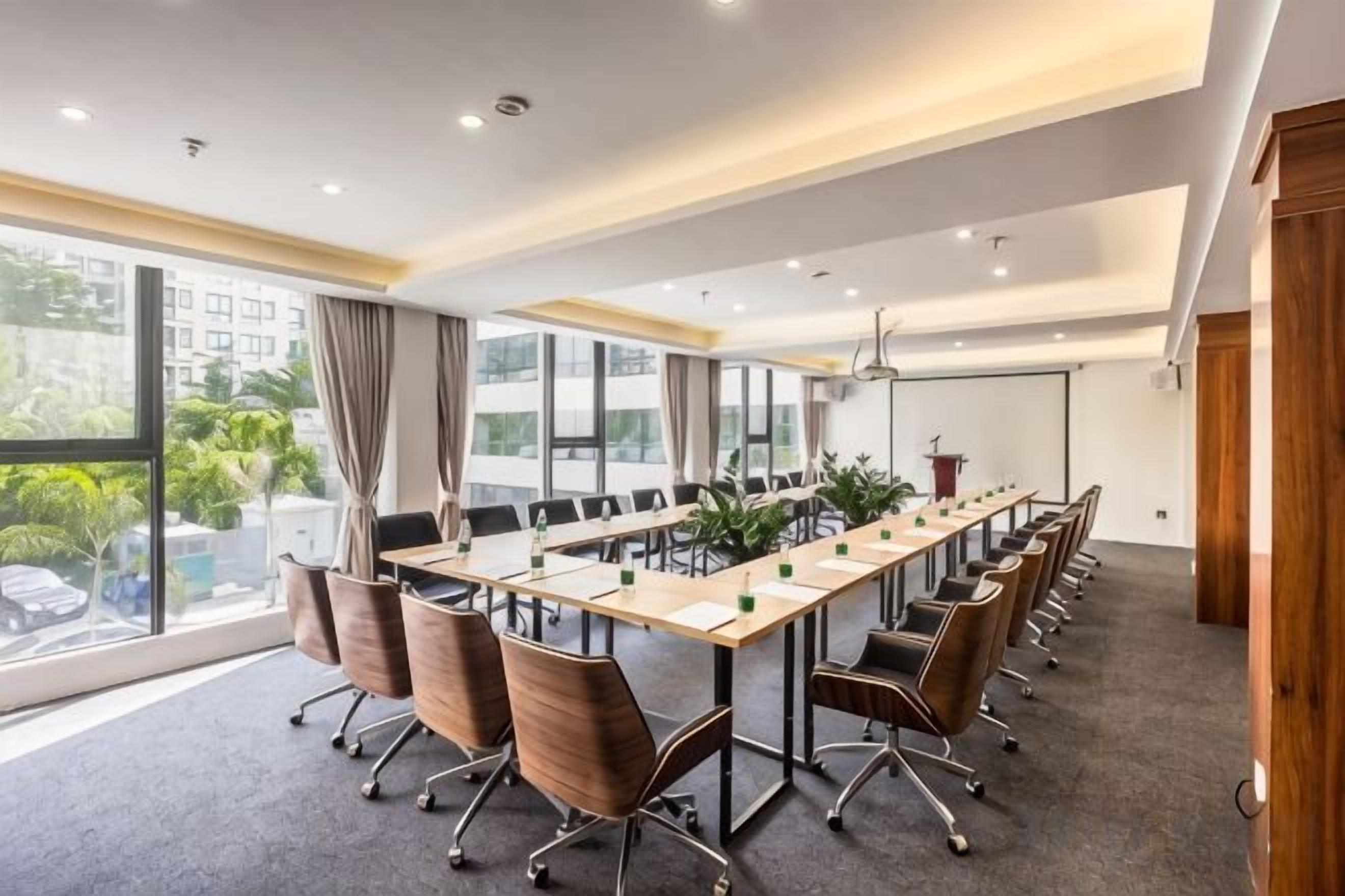 Sala de conferências com uma mesa comprida, cadeiras e vista através de grandes janelas.