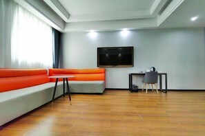 Uma sala de estar moderna com um sofá, uma mesinha, uma televisão e uma escrivaninha.