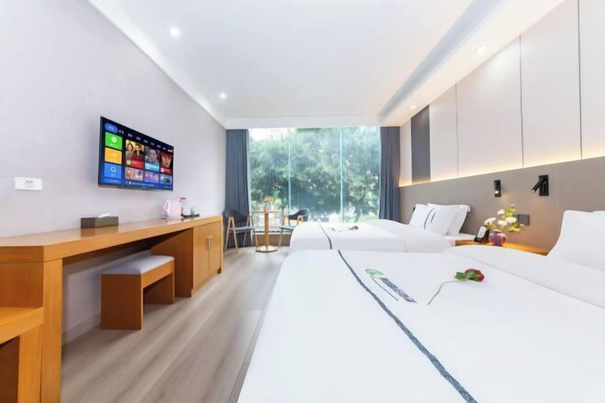 Quarto de hotel moderno com uma cama grande, uma escrivaninha e uma TV fixada na parede.