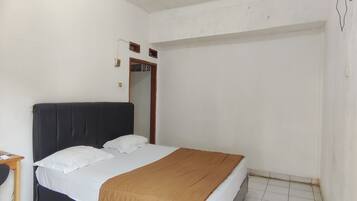 Quarto com cama, escrivaninha e televisão na parede.