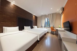 Quarto de hotel com duas camas, televisão, escrivaninha e janela com cortinas.
