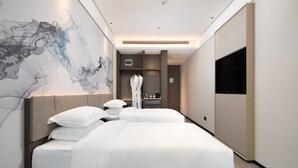 Quarto de hotel moderno com um grande mural abstrato, uma cama grande, uma TV e um roupão pendurado na parede.