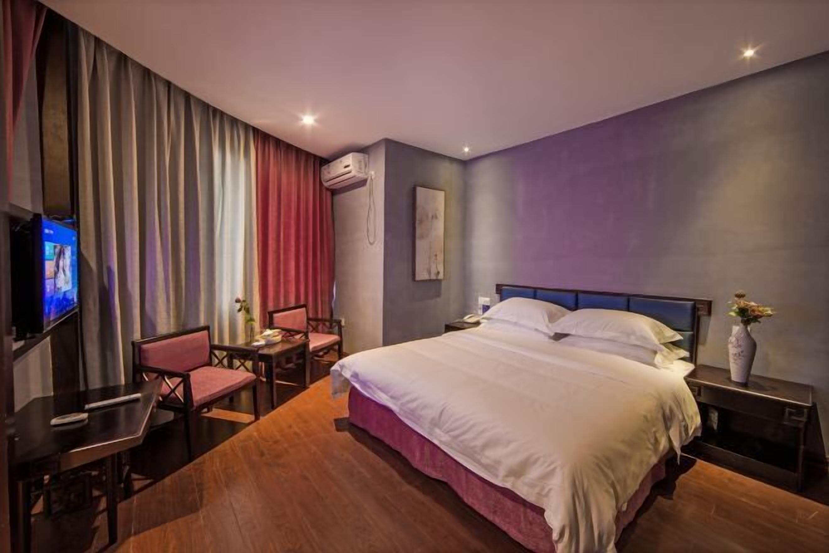Quarto de hotel com cama, escrivaninha, cadeira, televisão e ar condicionado.