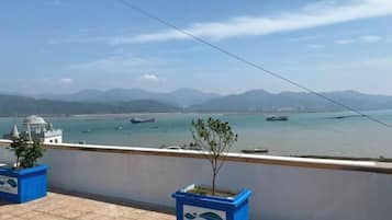 Varanda com vista para um mar tranquilo e montanhas ao longe.