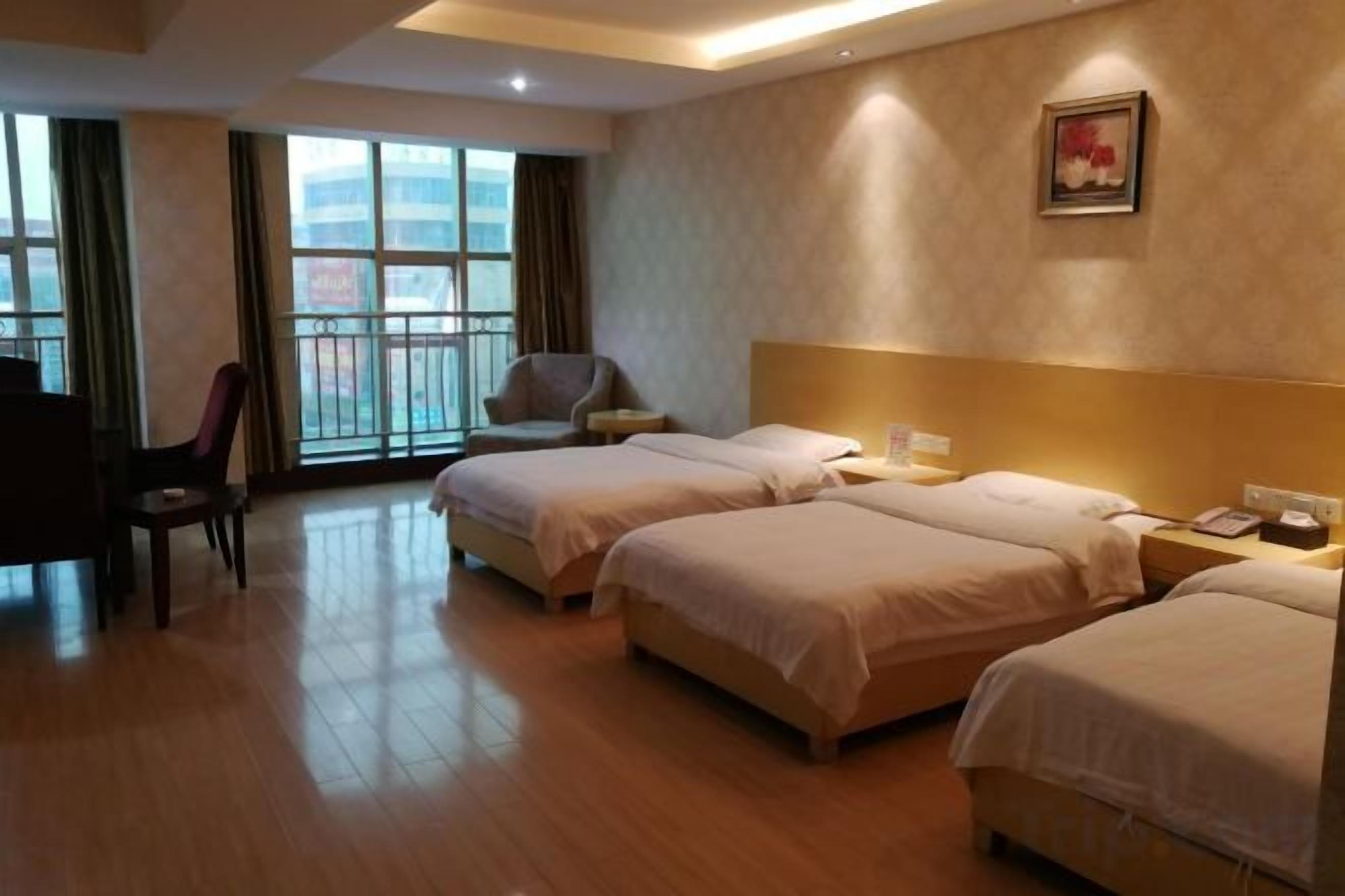 Quarto de hotel com duas camas, uma escrivaninha, uma cadeira e janela com vista.