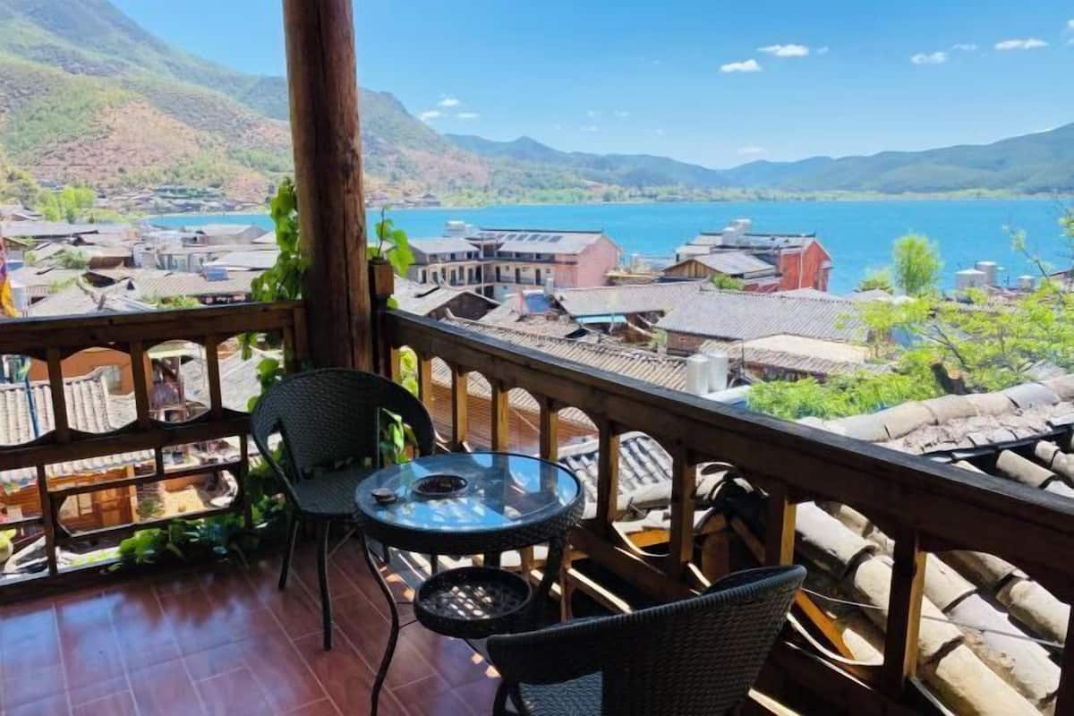 Uma varanda com mesa e cadeiras, com vista para uma cidade com edifícios tradicionais e um lago.