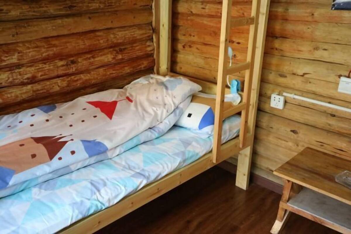 Uma cama beliche de madeira com travesseiro e cobertor.