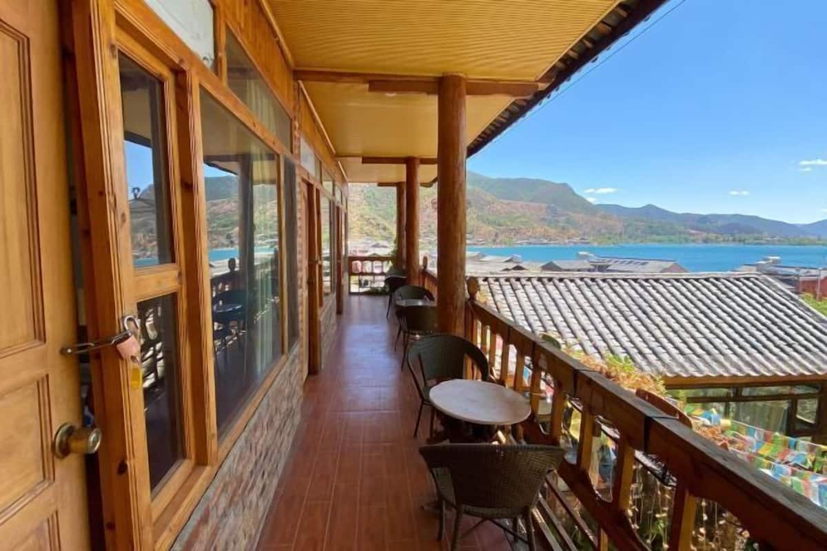Varanda de madeira com vista para um lago e montanhas.
