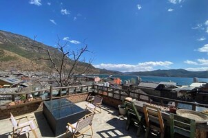 Terraço no telhado com vista para uma cidade e montanhas.