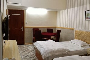 Quarto de hotel com duas camas, uma escrivaninha de madeira, uma cadeira e parede listrada.