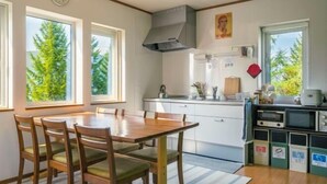 Uma cozinha com mesa de jantar, cadeiras, fogão e micro-ondas.