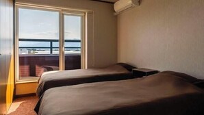 Quarto de hotel com duas camas, uma janela grande e ar condicionado.