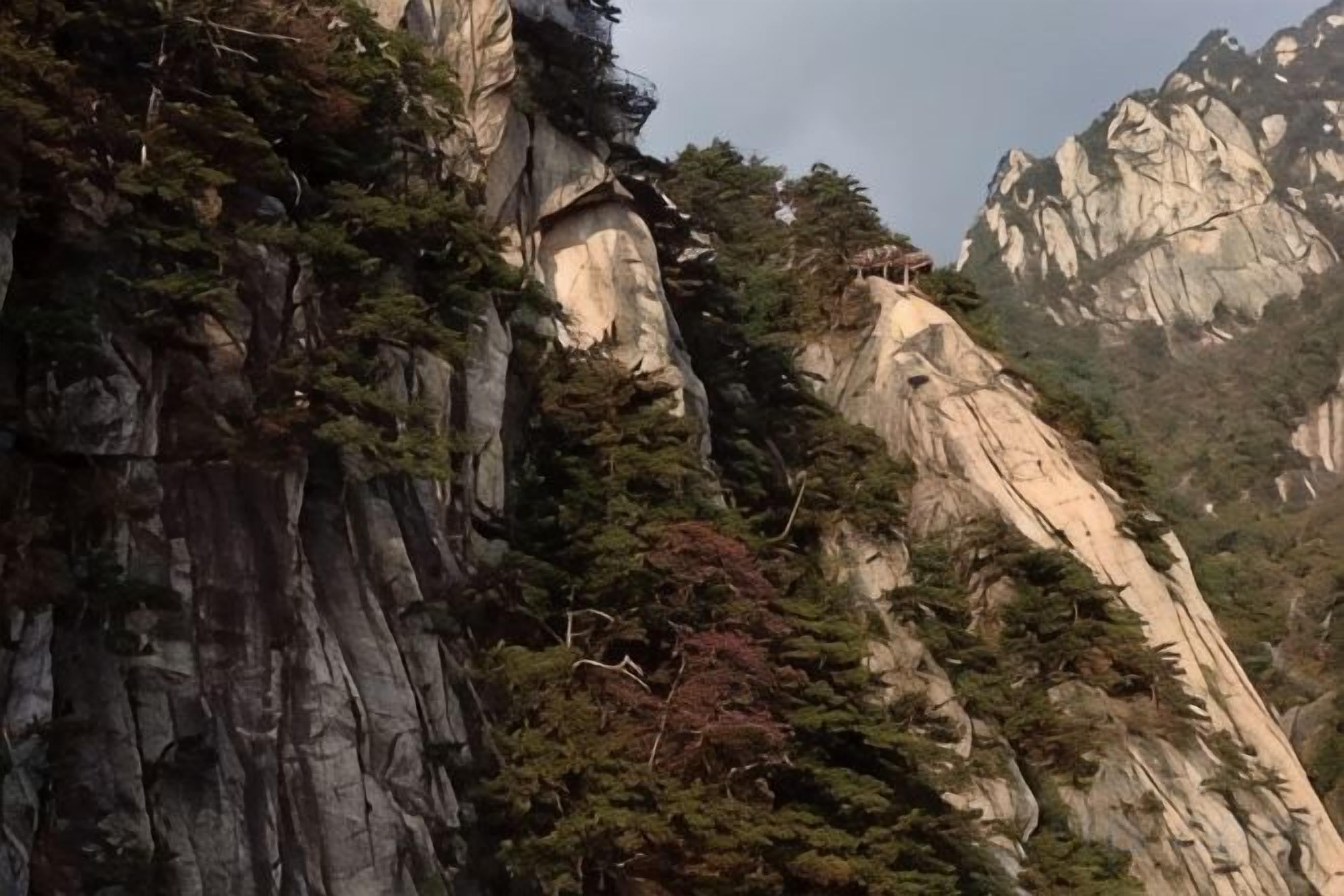 Paisagem montanhosa com penhascos rochosos e vegetação densa.