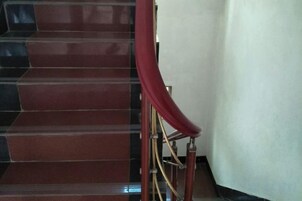 Uma escada com corrimão vermelho e piso coberto de carpete.