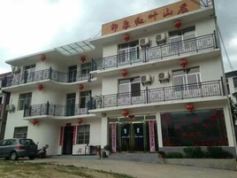 Hotel com vários andares, varandas, aparelhos de ar condicionado e lanternas vermelhas.