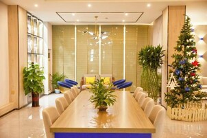 Uma sala de conferências com uma mesa comprida, cadeiras e um pinheiro de Natal.