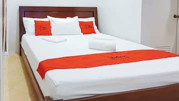 Uma cama bem arrumada com roupa de cama branca e vermelha, uma cabeceira de madeira e um cobre-leito vermelho com texto.