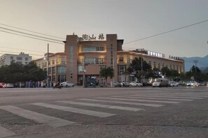 Edifício de vários andares com entrada imponente e faixa de pedestres à frente.