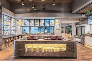 Restaurante com balcão de mármore, diversas vitrines de comida e design de interiores moderno.