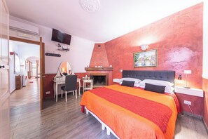 Quarto com cama, escrivaninha, cadeira, televisão e lareira.