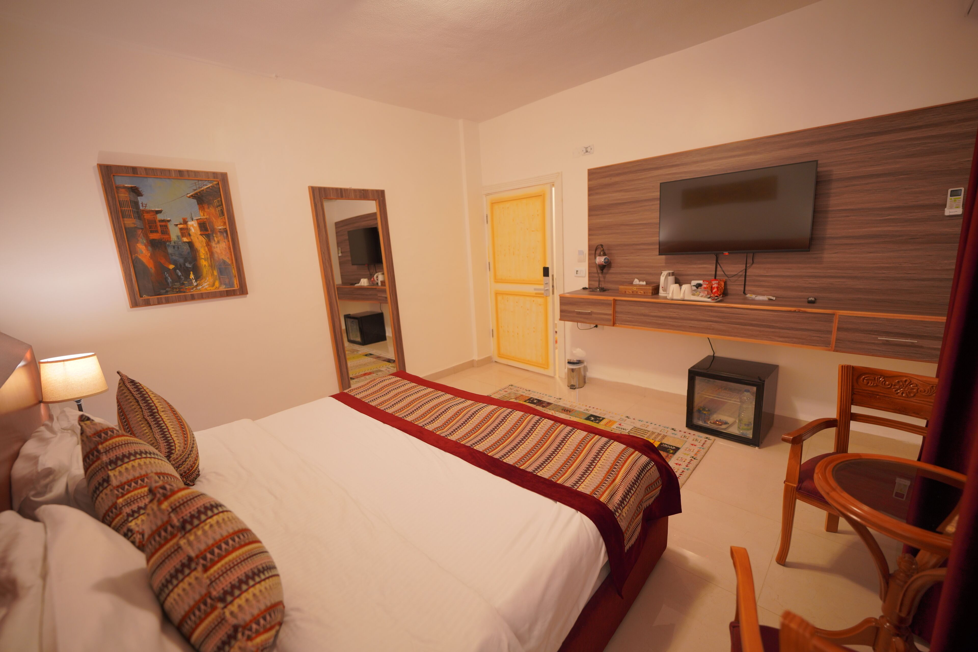 Quarto de hotel com uma cama, televisão, armário de madeira, cadeira e um pequeno aquecedor.
