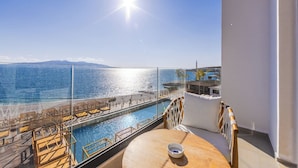 Uma varanda com vista para uma piscina e o mar.
