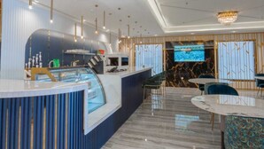 Um hall de hotel moderno com piso de mármore, balcão de recepção, área de bar e assentos.