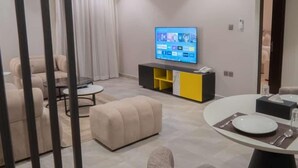 Sala de estar moderna com sofá, um banquinho e uma mesa de jantar para dois.