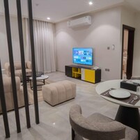 Sala de estar moderna com sofá, um banquinho e uma mesa de jantar para dois.