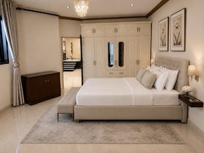 Quarto com uma cama grande, um guarda-roupa, uma mesa de cabeceira e um candelabro.