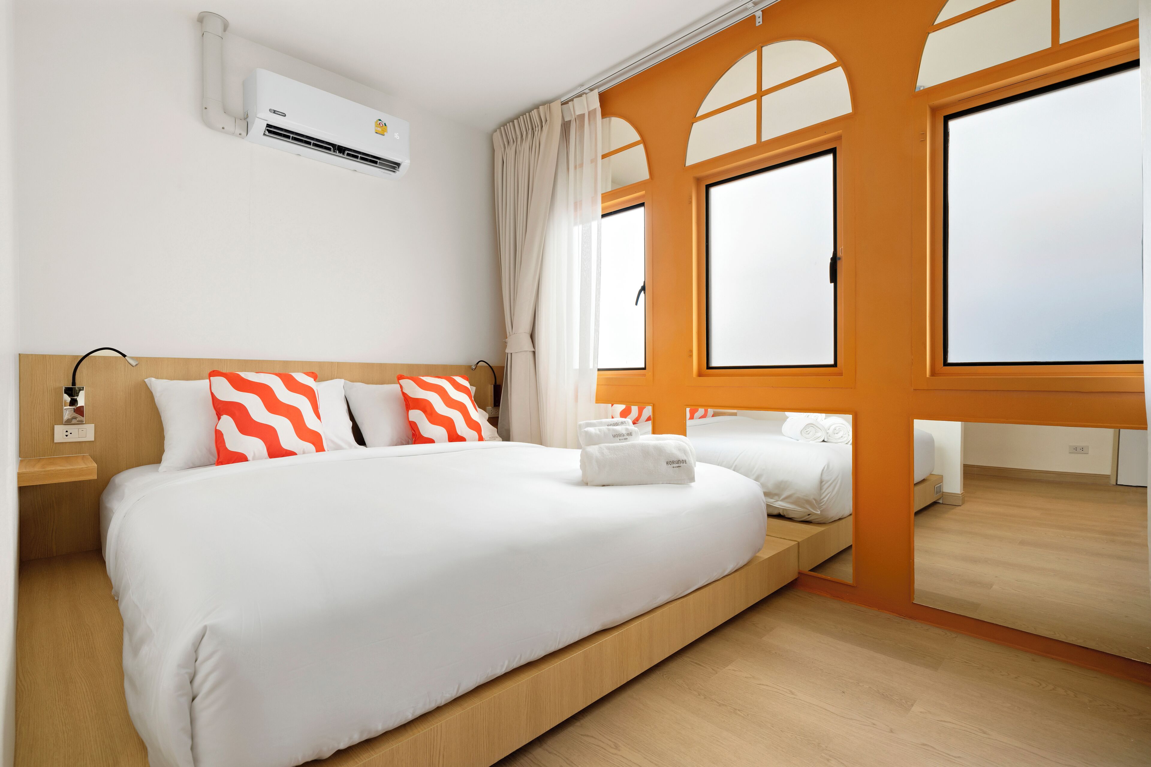 Quarto de hotel com uma cama grande, mesa de cabeceira, ar condicionado e janela com cortinas.