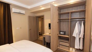 Quarto de hotel com cama, escrivaninha, closet espaçoso e ar condicionado.