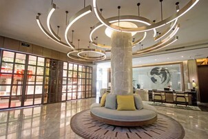 Um saguão com uma coluna central, um espaço de estar circular e um balcão de recepção.