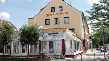 Hotel Zum Riesenbaum com uma estufa de vidro e fachada vermelha.